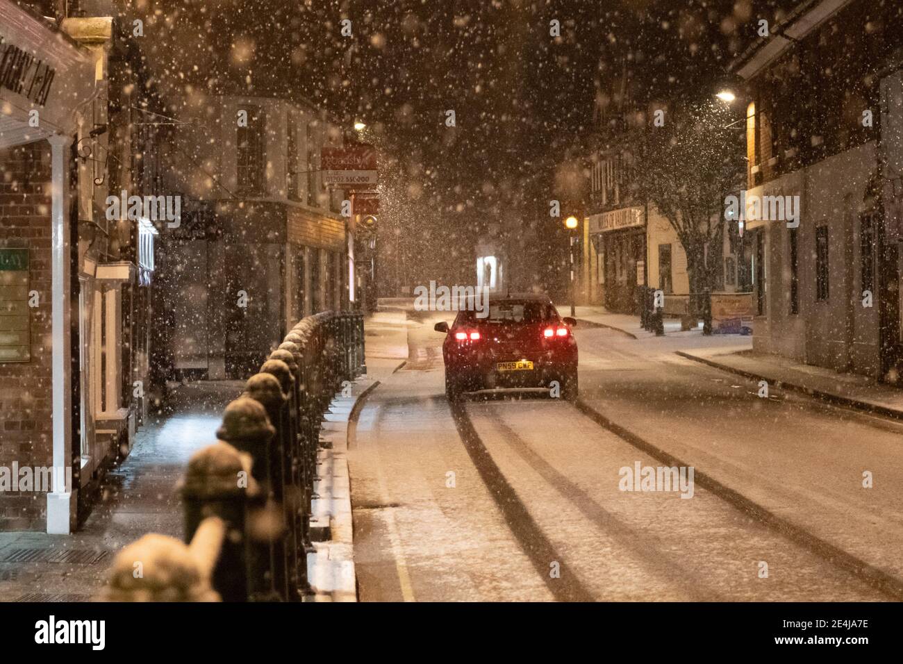 Falling snow on high street at night. Driving car in snow with tyre ...