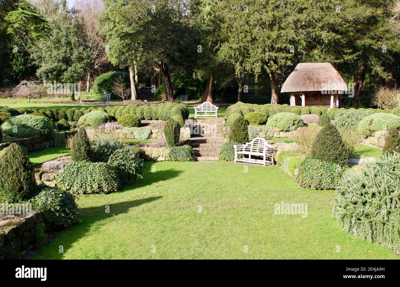 Sunken garden at West Dean gardens with seating and rustic, thatched ...