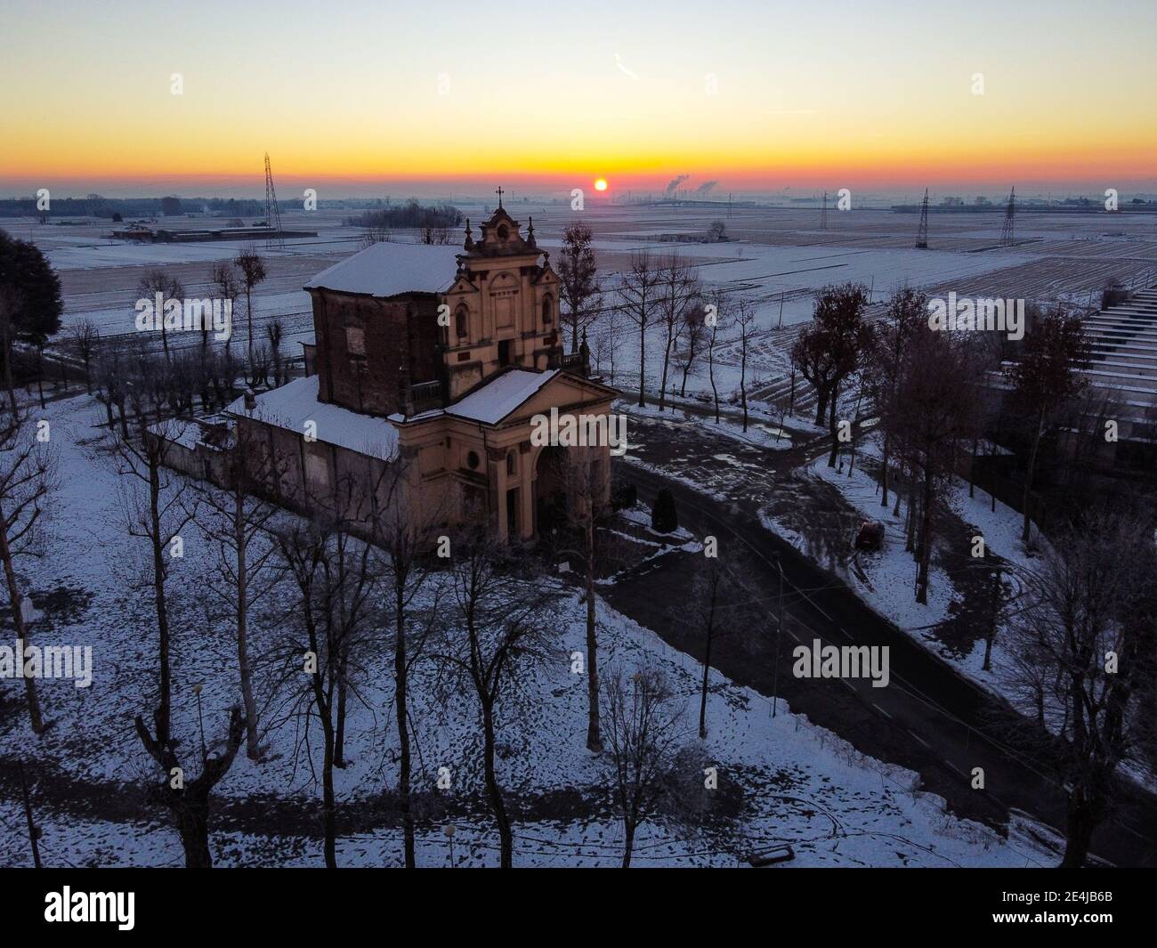 Sun rising over the snowy plain and the sanctuary of Varallino di ...