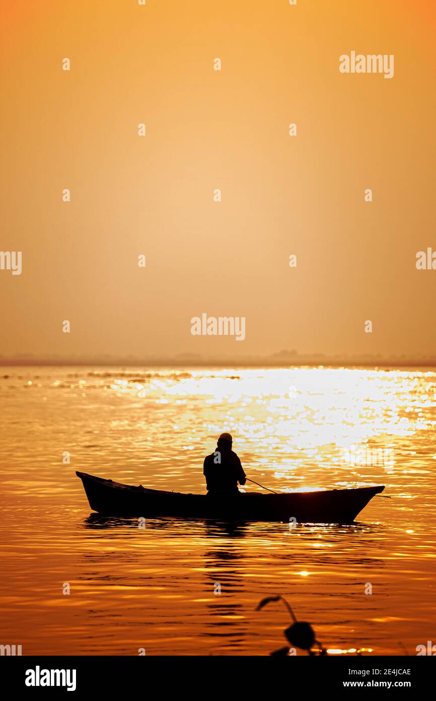 Evening golden sunset time, a fisherman fishing on the seaside on a ...