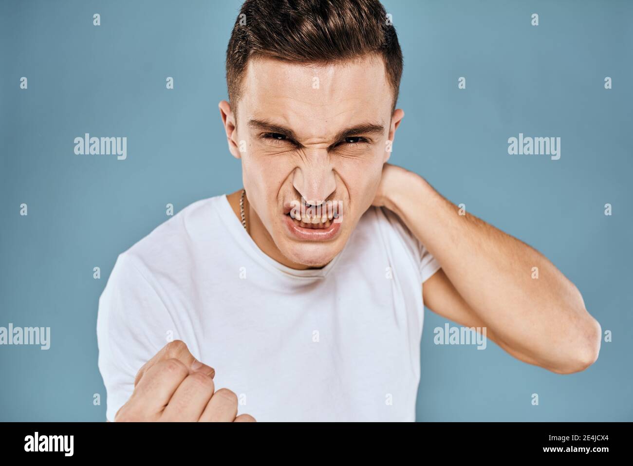 emotional displeased man cropped view white t-shirt blue background ...