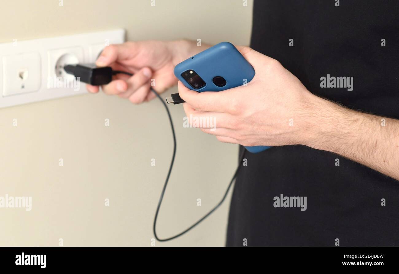 Hand holding smartphone and preparing for charging Stock Photo - Alamy