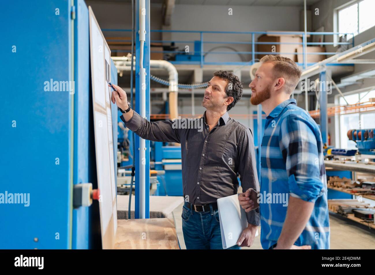 Two carpenters talking over documents in production hall Stock Photo - Alamy