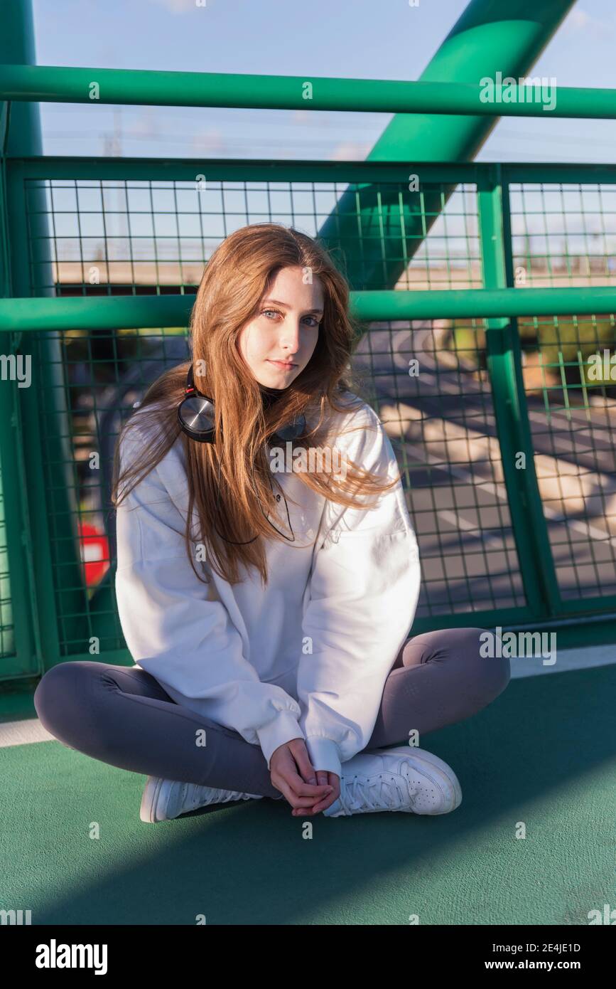 Teenage girl staring while sitting on bridge Stock Photo - Alamy