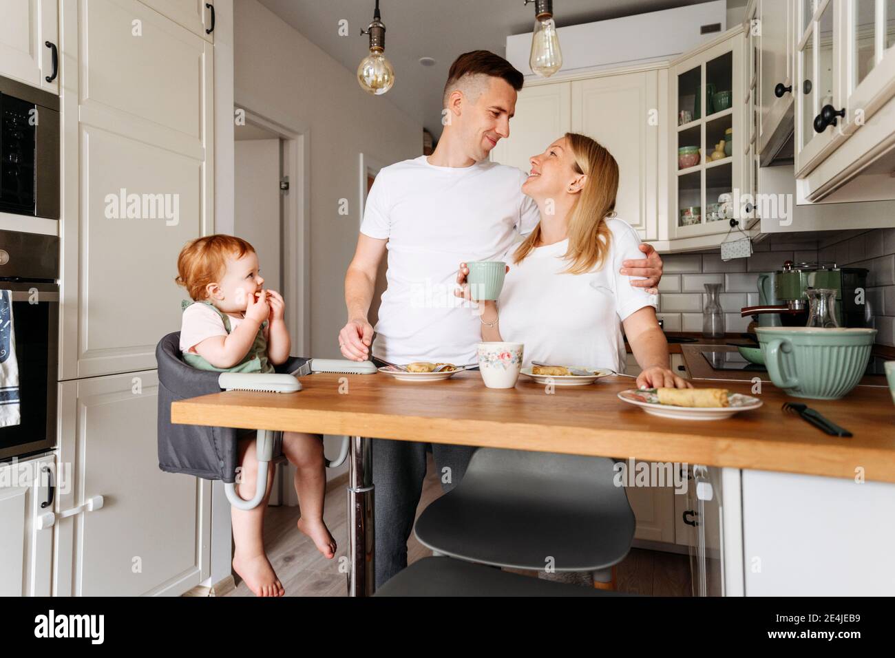 Happy family with baby daughter at kitchen table Stock Photo - Alamy