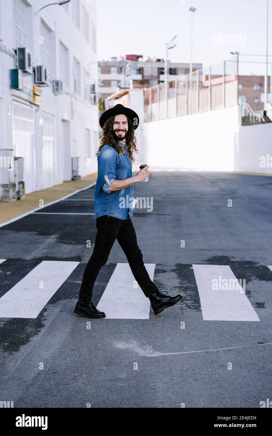 Happy young man walking on street in city Stock Photo - Alamy