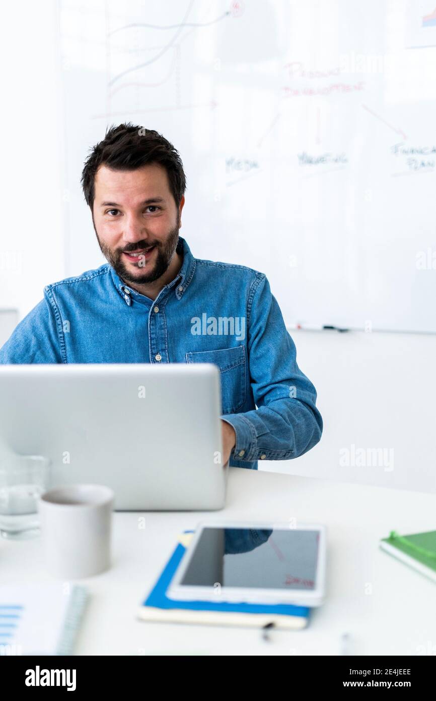 Portrait of smiling man using laptop in office Stock Photo - Alamy