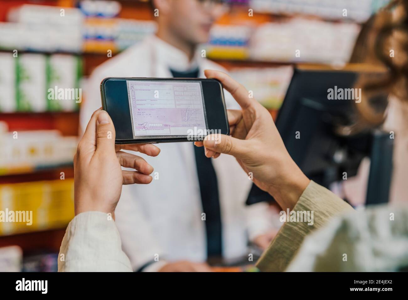 Hand of customer using smart phone for prescription in chemist store ...