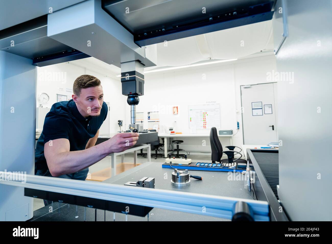 Male technician adjusting drill bit in machine at industry office Stock ...