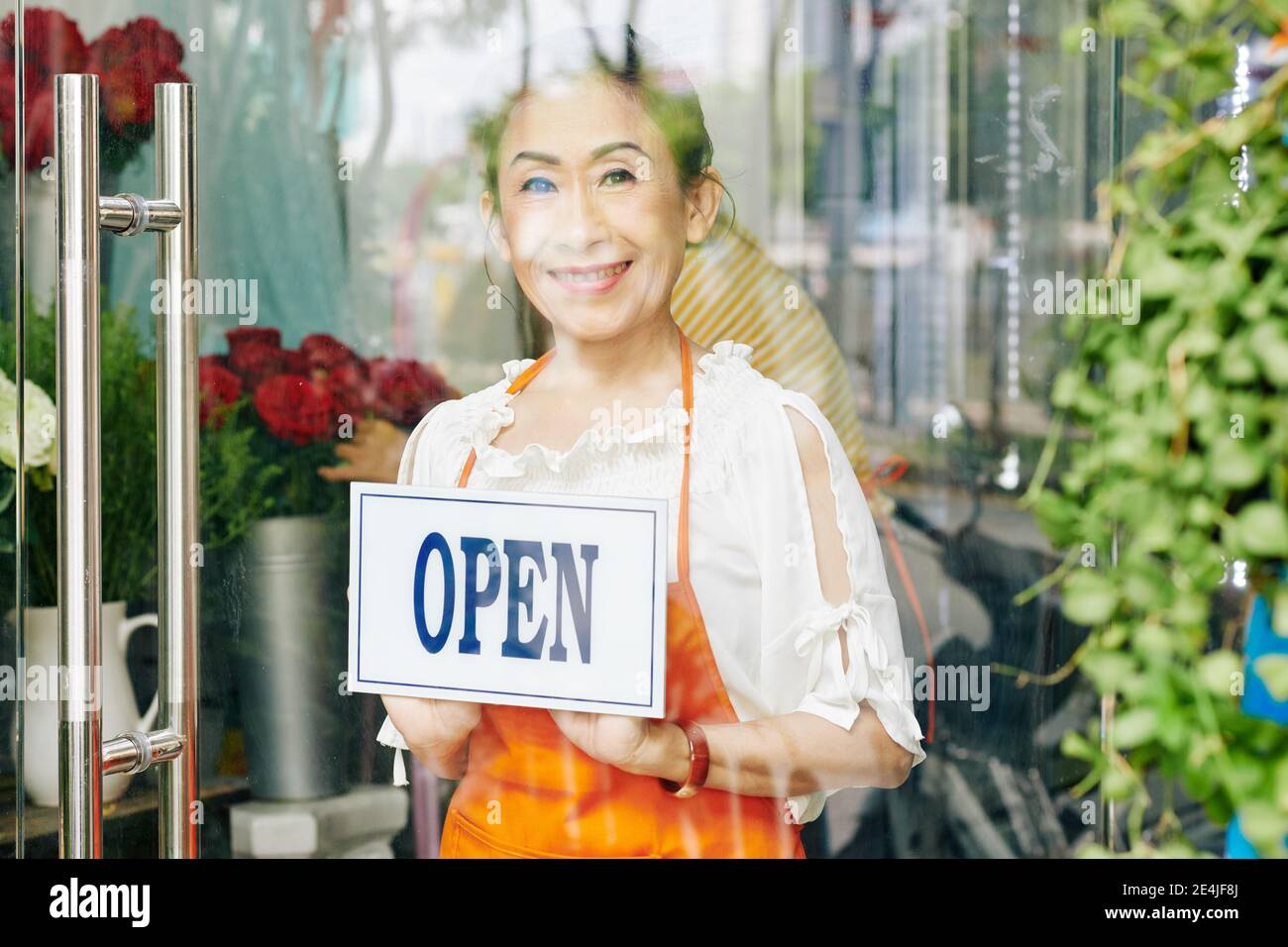 Flower shop owner turning open sign Stock Photo - Alamy