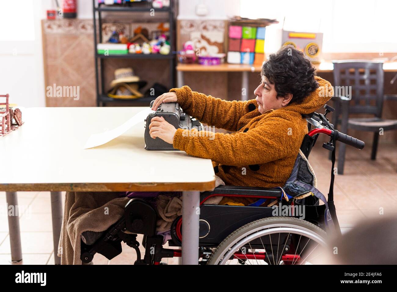 Disabled woman typing on typewriter while sitting on wheelchair in ...