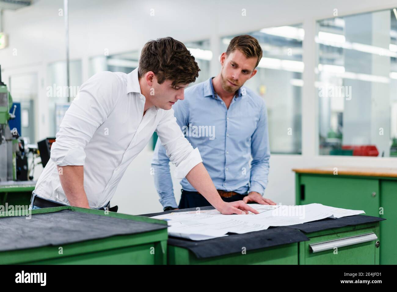 Male entrepreneur looking at engineer while working on floor plan in ...