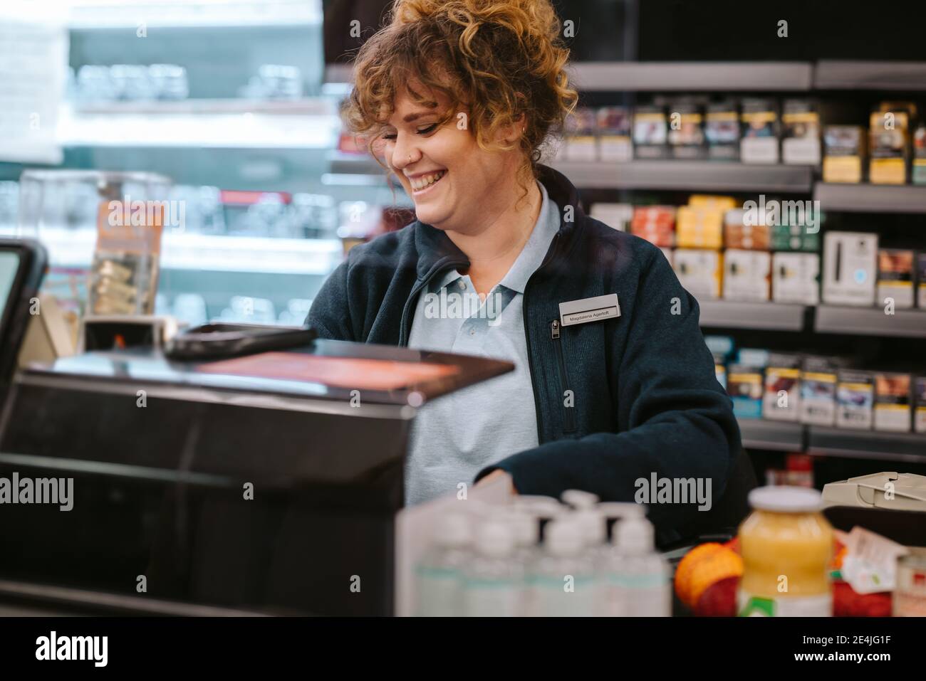 Happy female cashier working at a supermarket. Woman working at local ...
