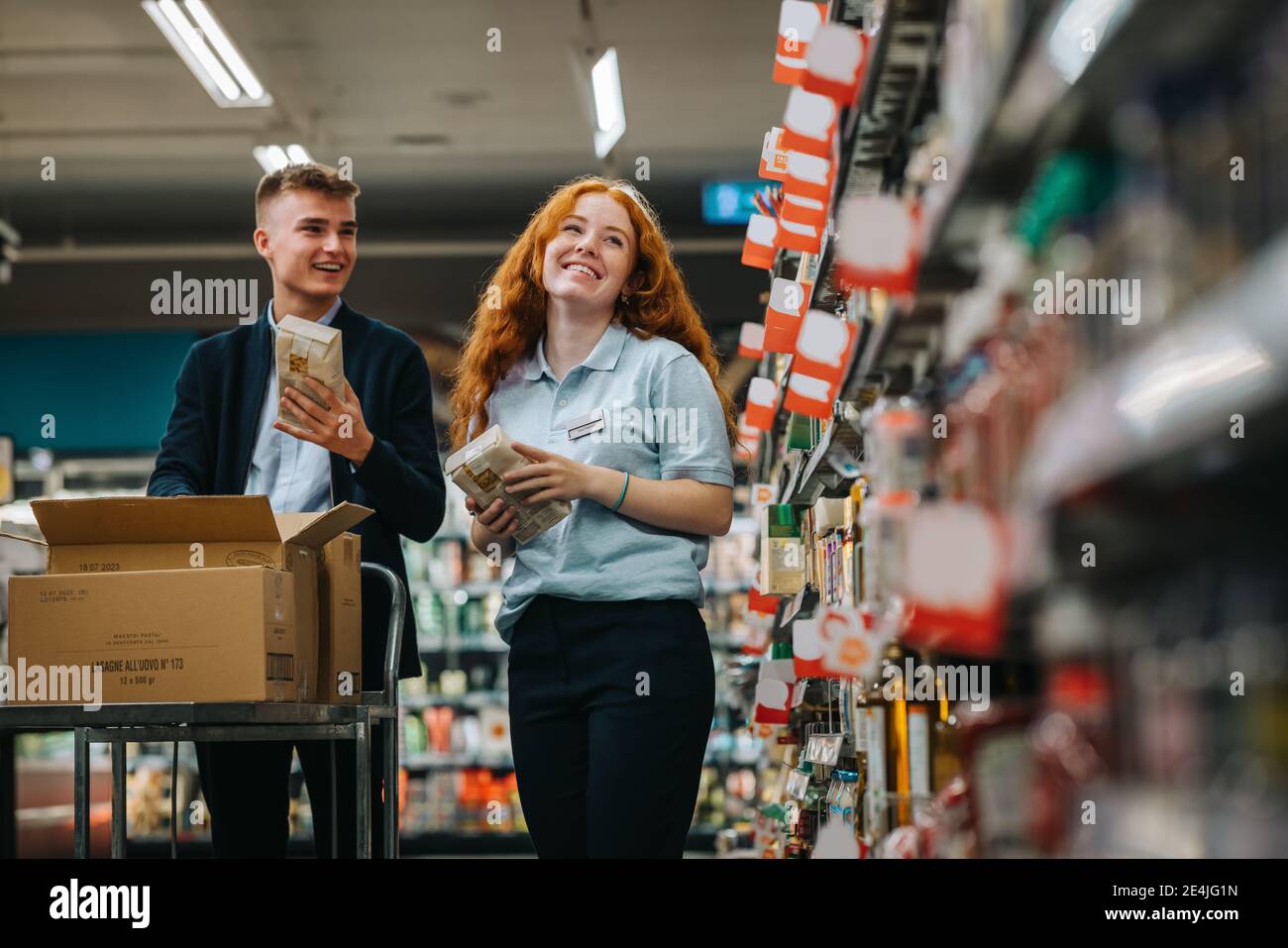 Man and woman working at a supermarket restocking the shelves. Two ...