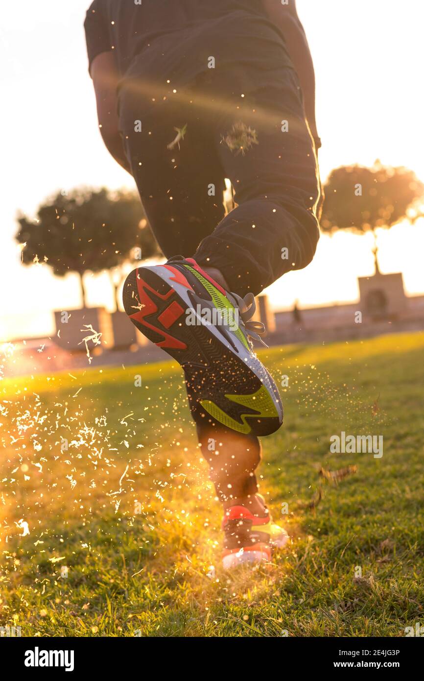 Legs of young man running on grassy land in park at sunset Stock Photo ...
