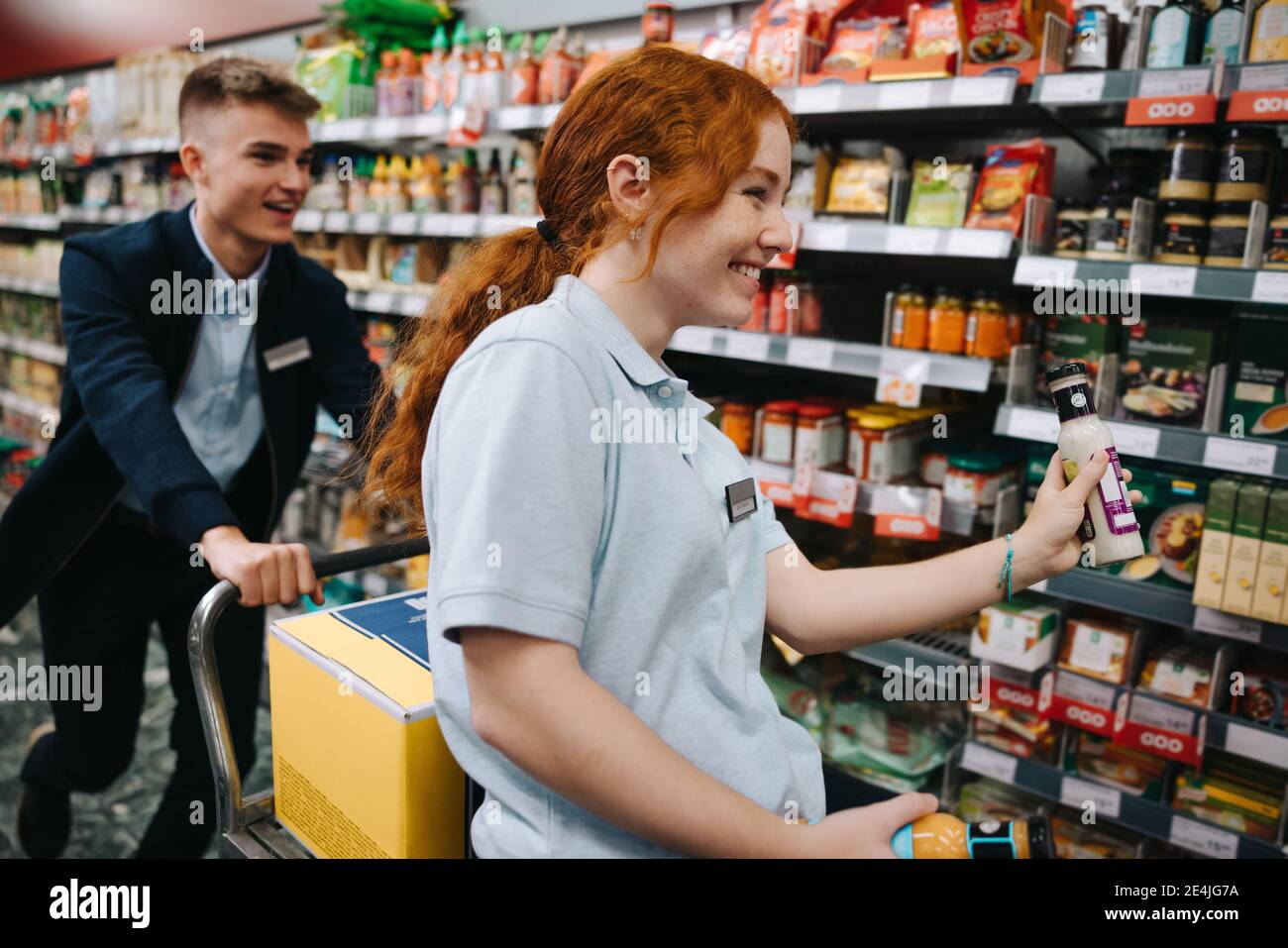 Supermarket employees having fun while working. Man pushing woman on ...
