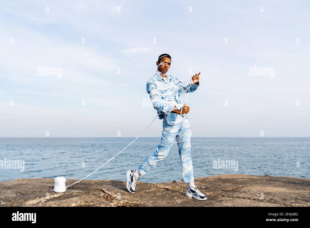 Man trapped in rope struggling to set free while standing against sea ...