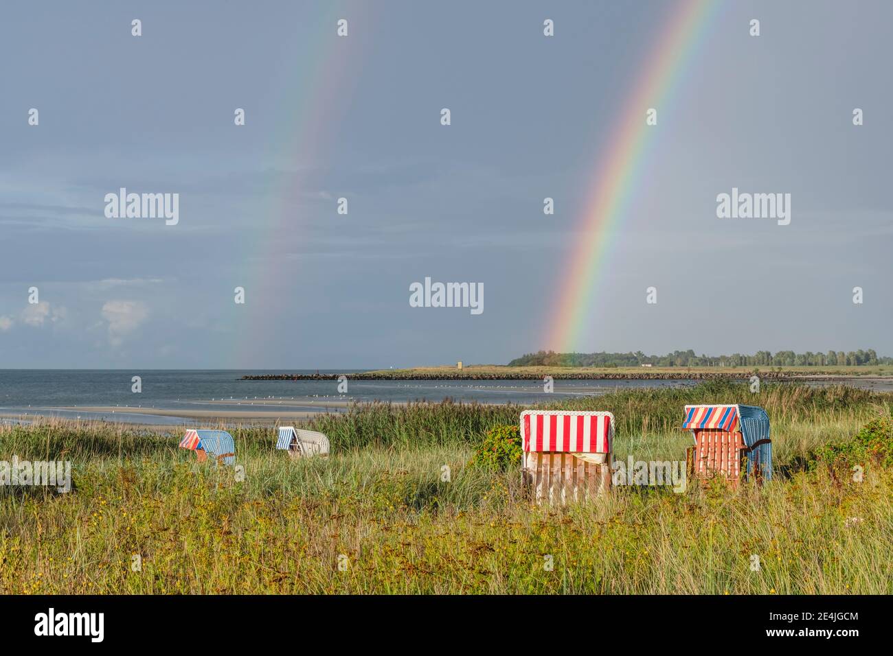 Double rainbow arching over hooded beach chairs standing on grassy ...