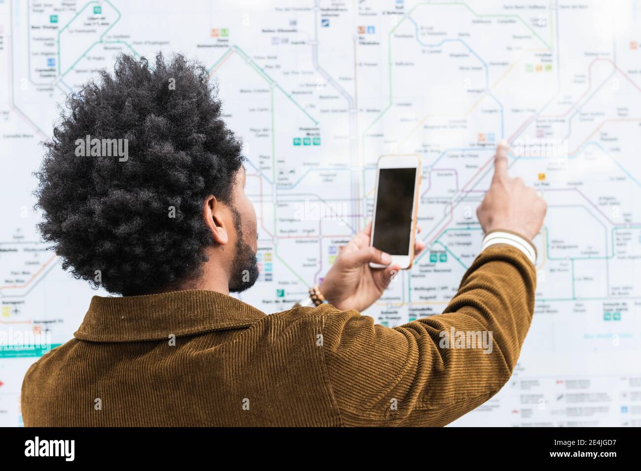 Man with afro hair using smart phone while analyzing map Stock Photo ...