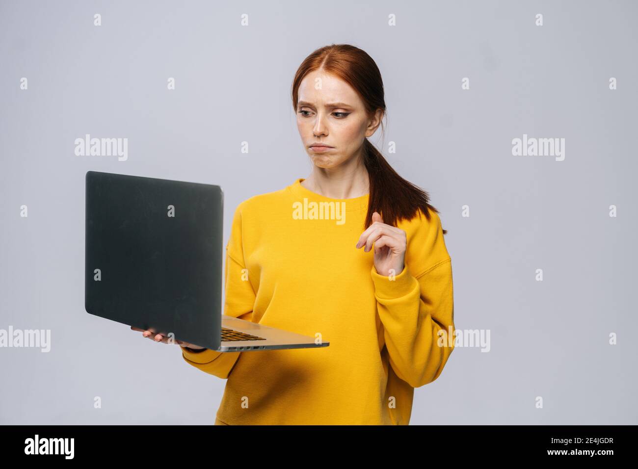 Sad young woman student holding laptop computer and typing on isolated ...