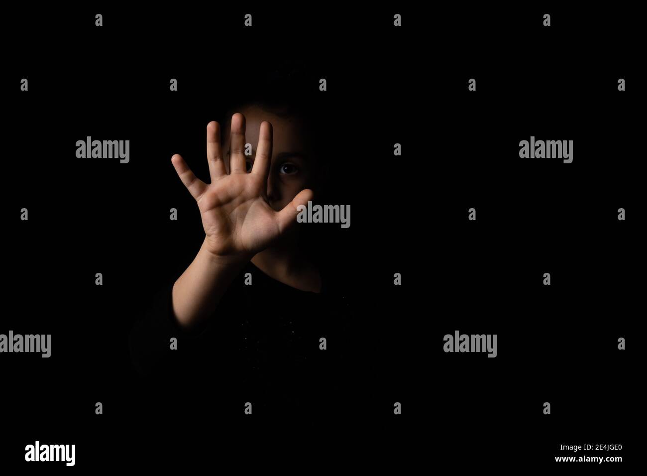 little girl with a raised hand making a stop sign gesture on a black ...