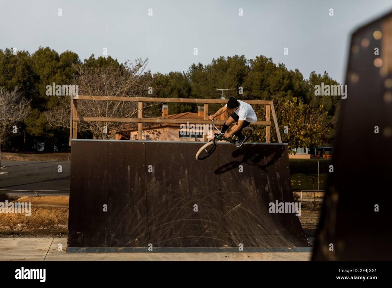 Young man doing stunt on ramp at bike park during sunny day Stock Photo ...