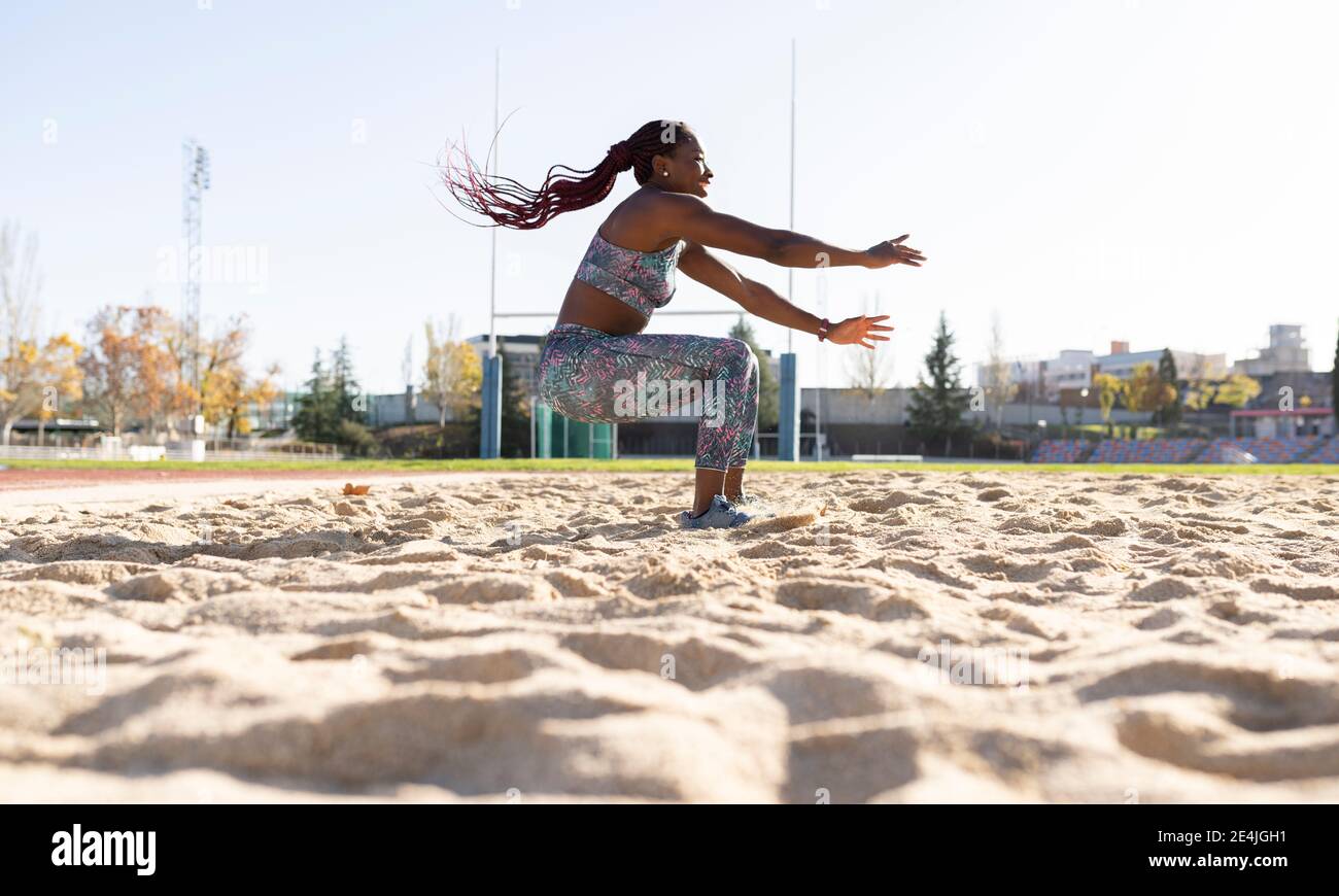 Female sportsperson balancing on sand against clear sky during sunny ...