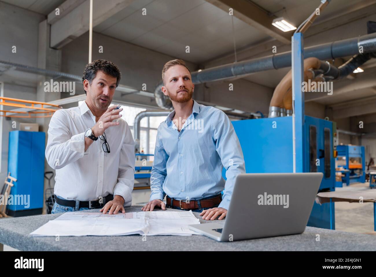 Two carpenters talking over documents in production hall Stock Photo - Alamy