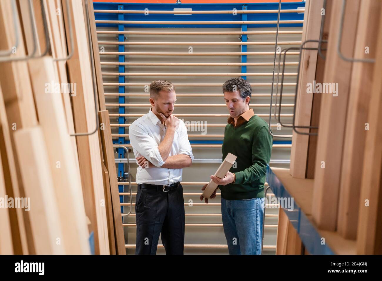 Two carpenters talking in production hall with wooden planks in ...
