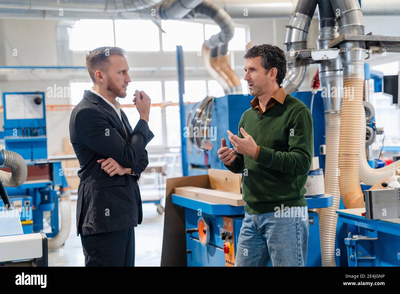 Two carpenters standing and talking in production hall Stock Photo - Alamy