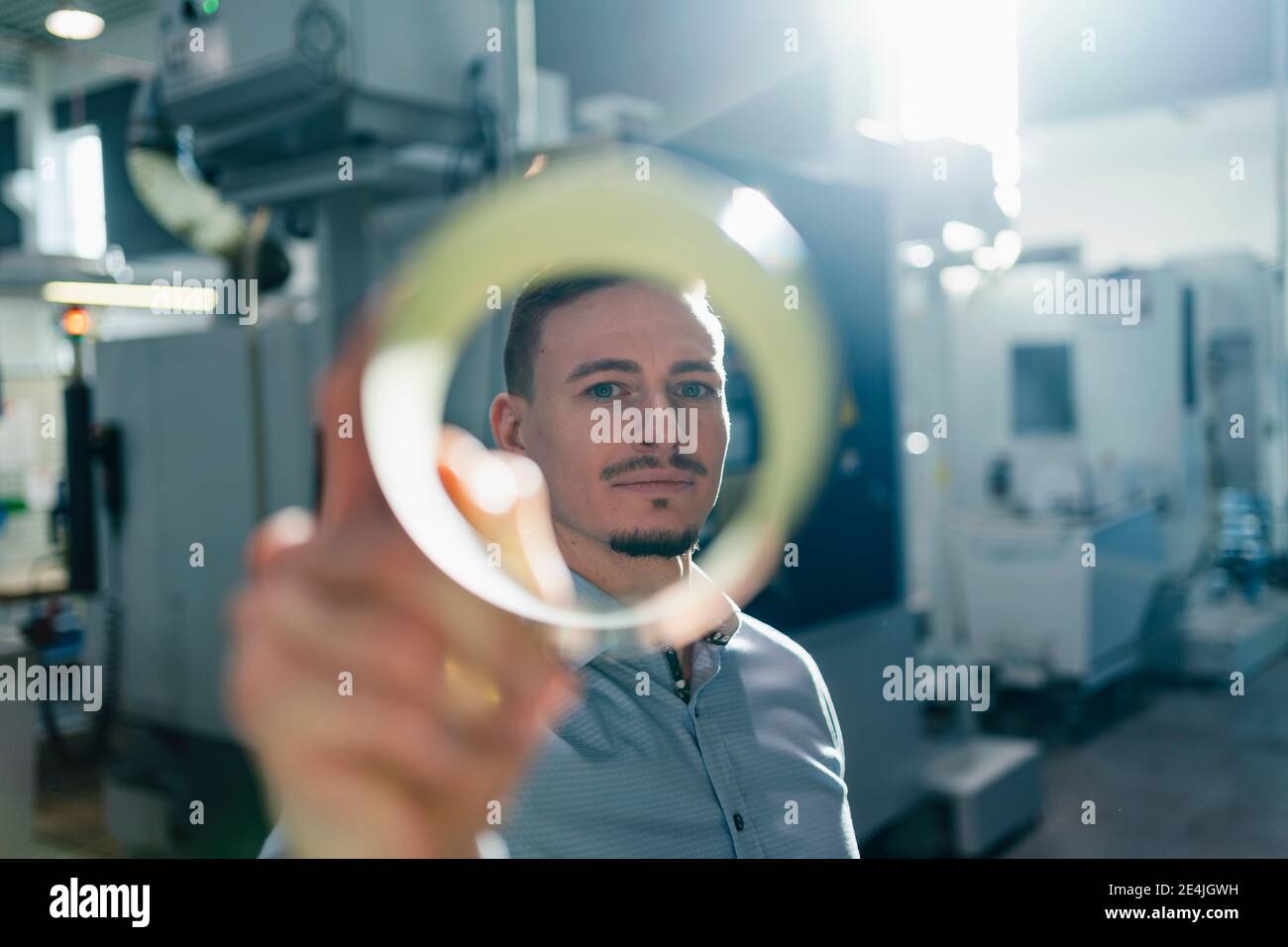 Mid adult businessman seen through circular equipment in factory Stock ...