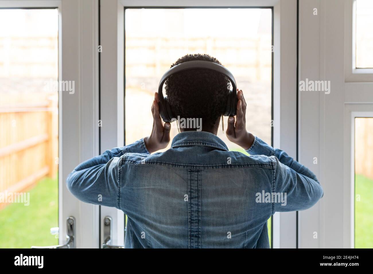 Woman with headphones looking through window Stock Photo - Alamy