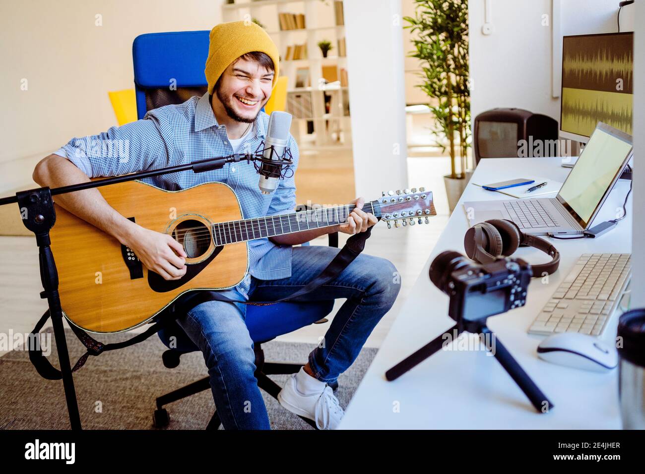 Happy musician playing guitar while recording on camera at recording ...