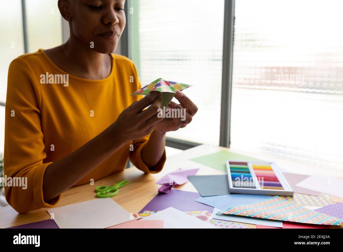 Origami artist sitting in studio working with colorful paper Stock ...
