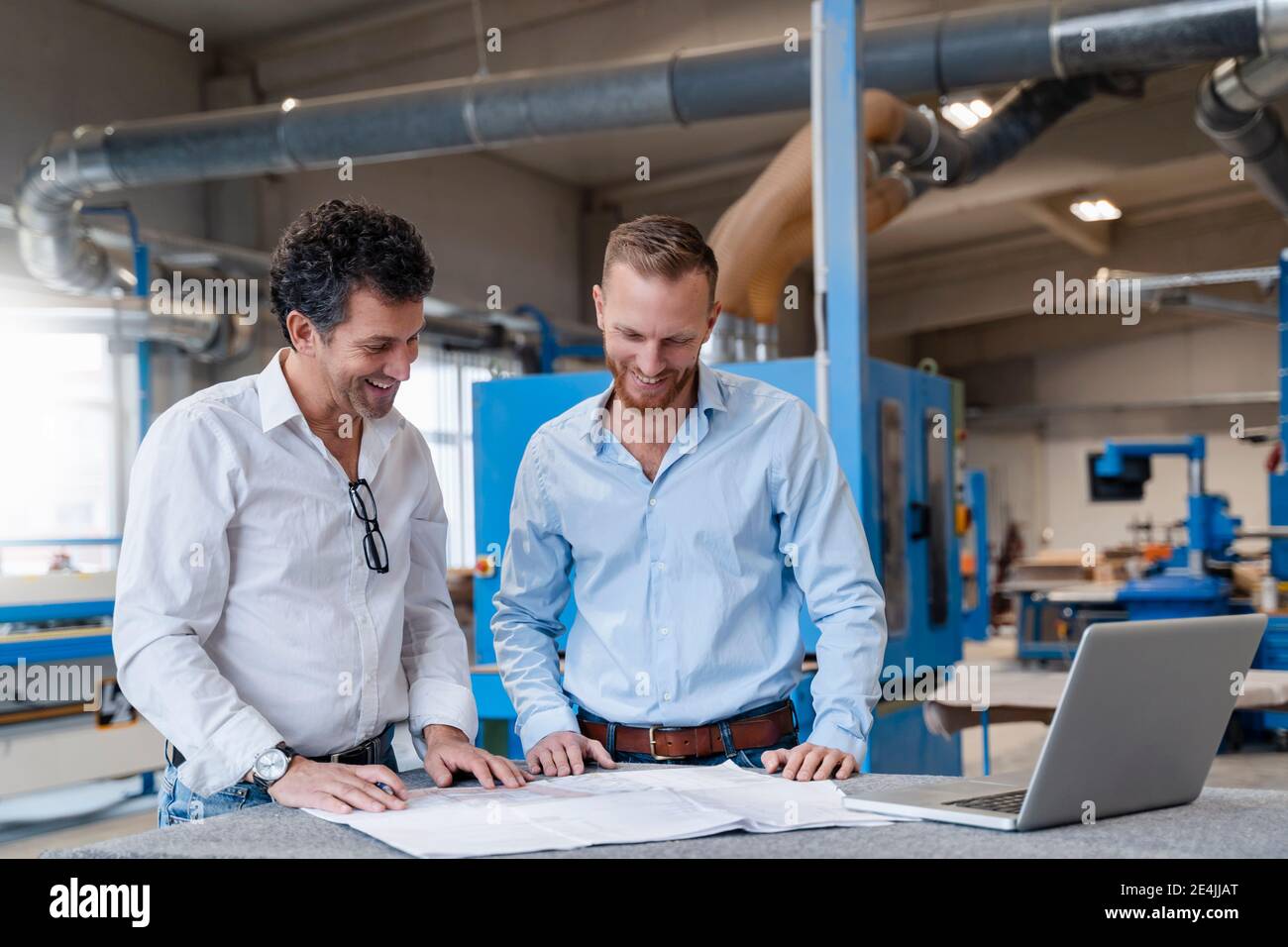 Two carpenters talking over documents in production hall Stock Photo ...