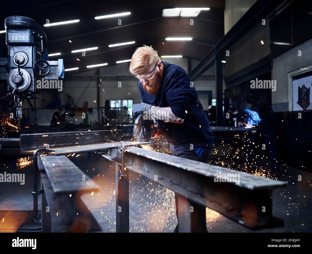 Welder using circular grinder while working at factory Stock Photo - Alamy