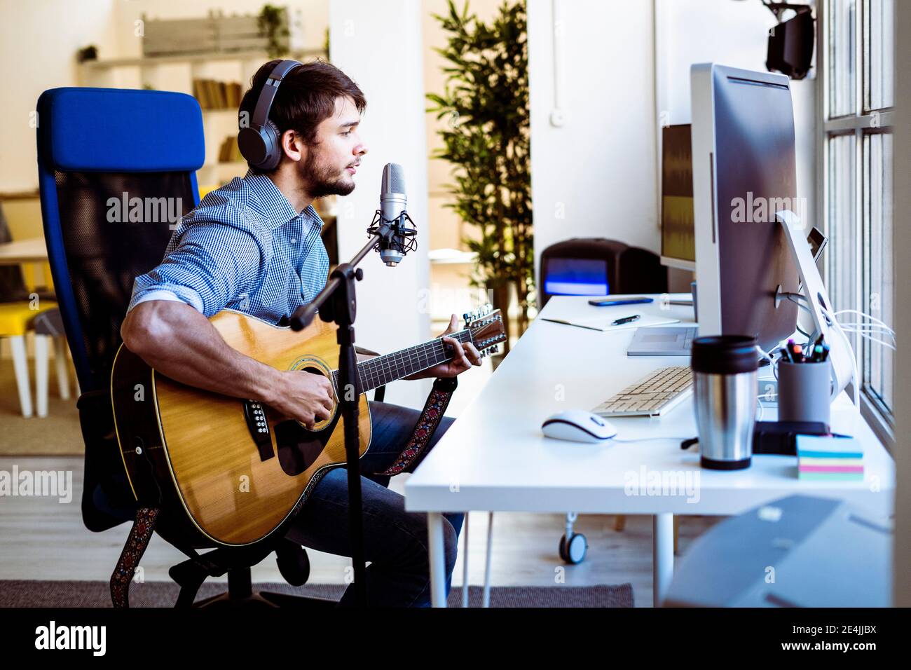 Musician singing while playing guitar at recording studio Stock Photo ...