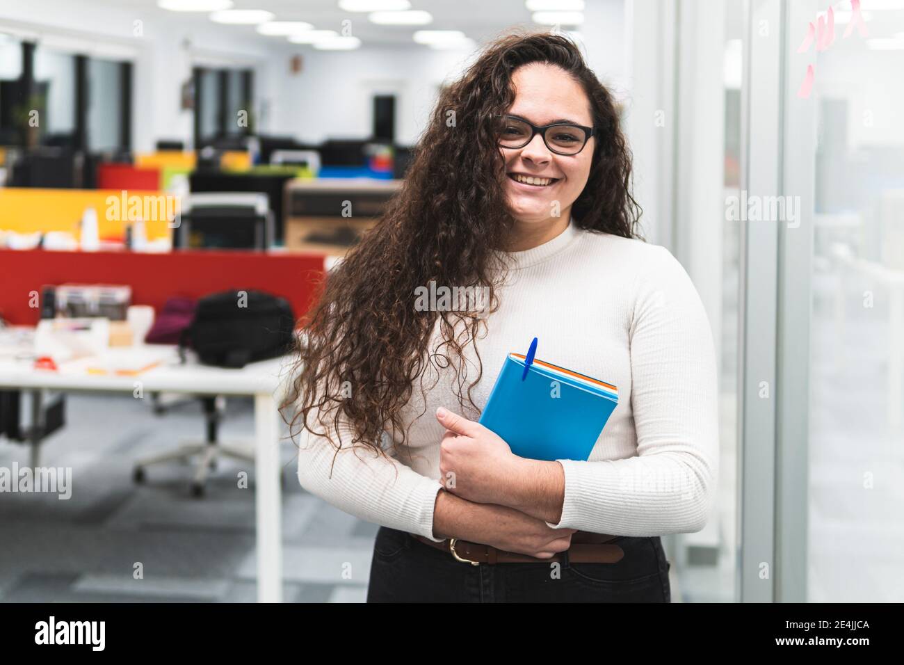 Happy female professional with diary and pen at work place Stock Photo ...