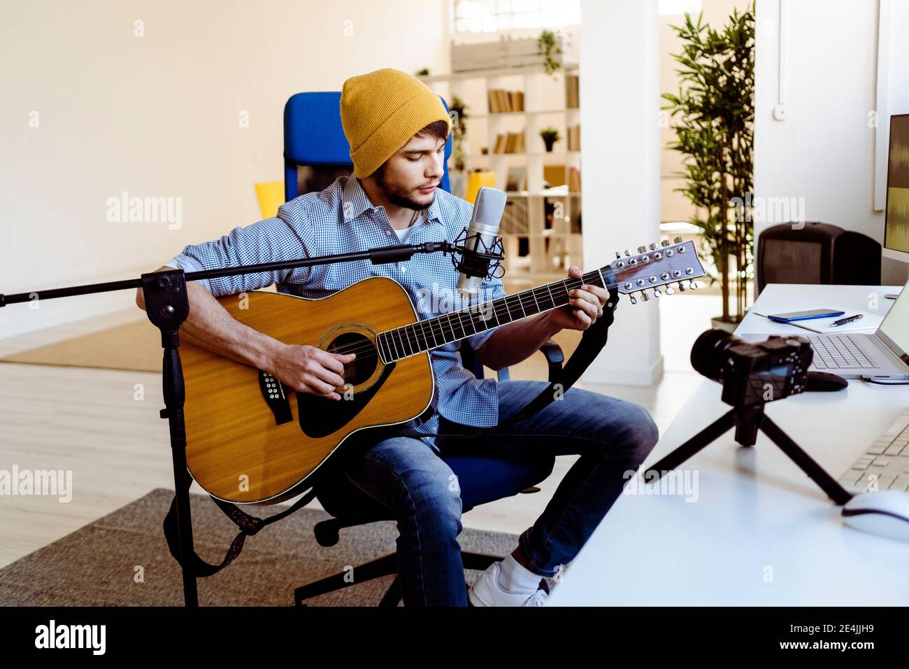 Musician playing guitar while streaming live through camera at ...