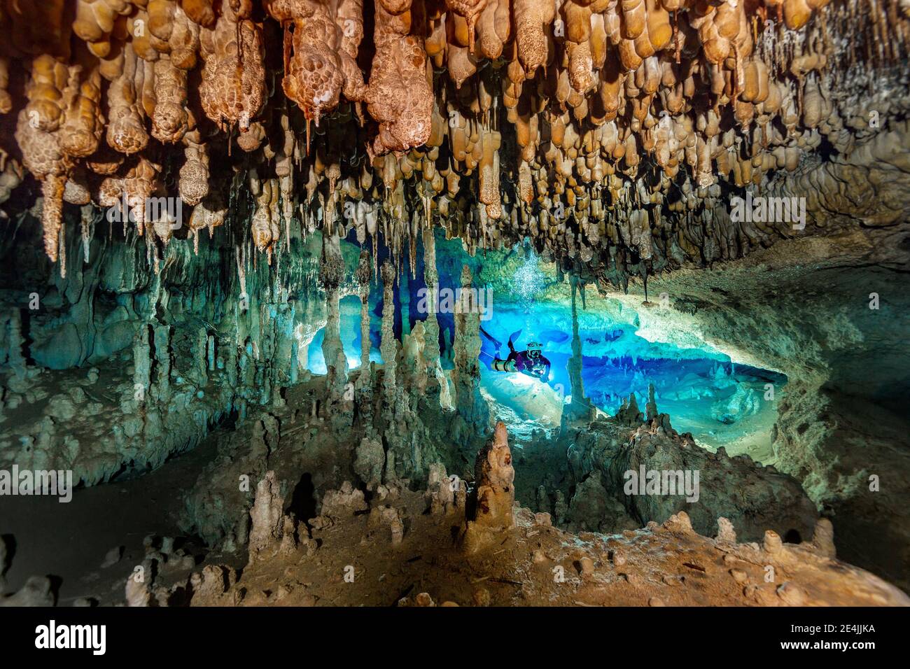 Male diver exploring amidst rock formation in sea, Cenote Nariz ...