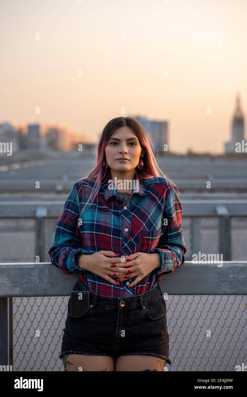 Hipster young woman leaning on railing during sunset Stock Photo - Alamy