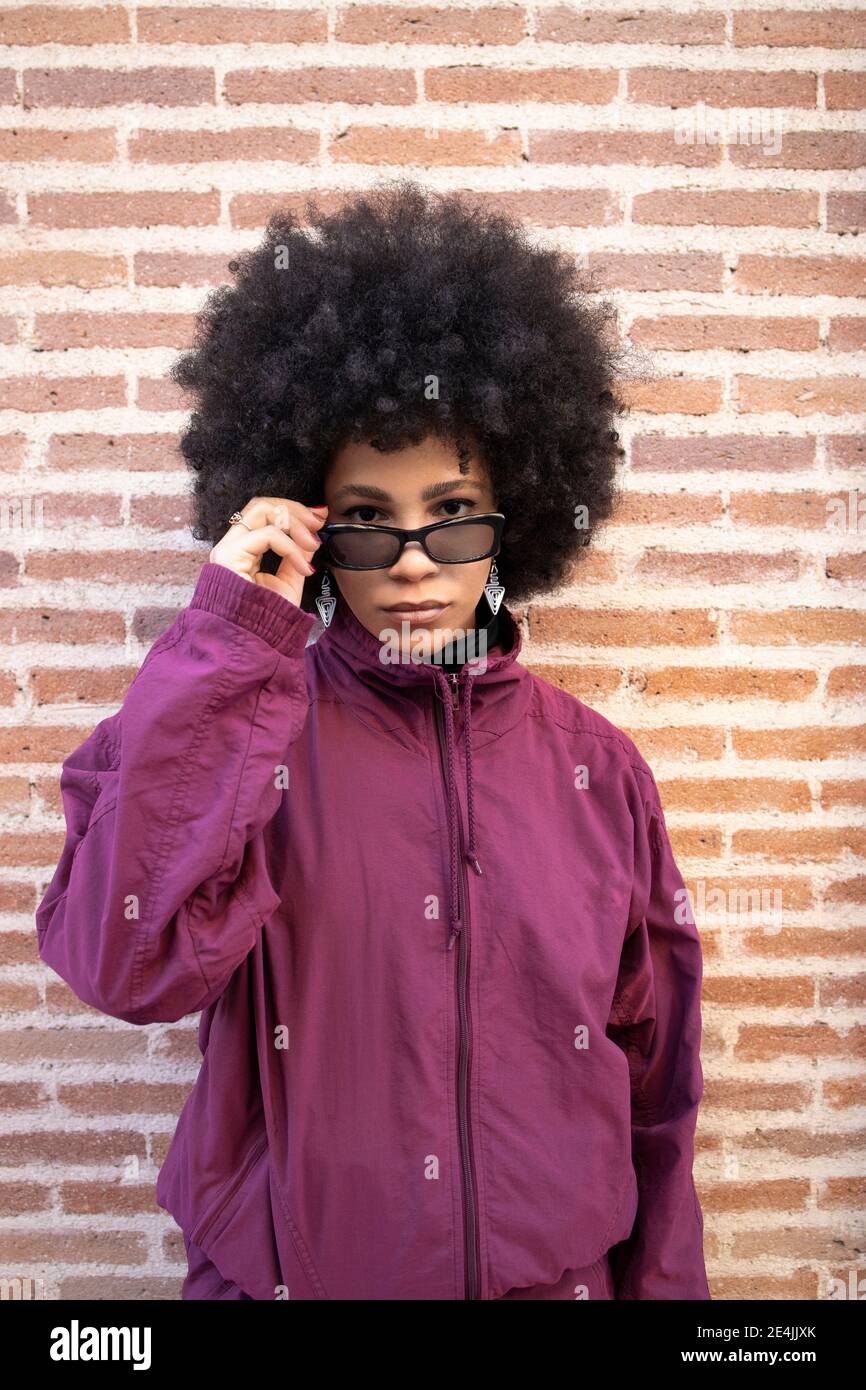 Fashionable young woman wearing warm clothing against brick built ...