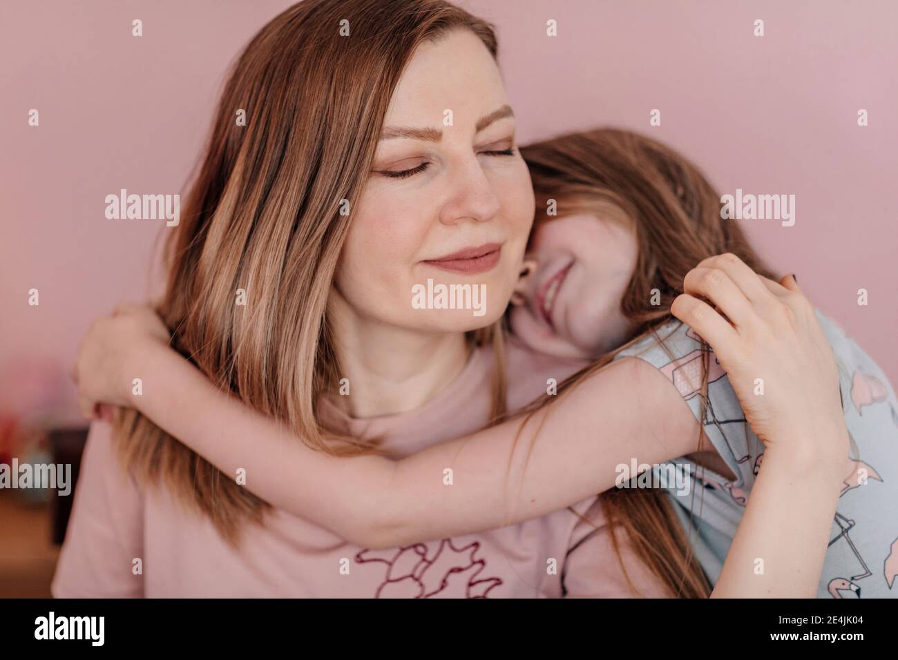 Daughter embracing mother against wall at home Stock Photo - Alamy