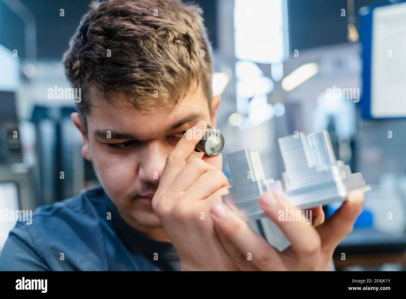 Engineer with small microscope examining model while standing at ...