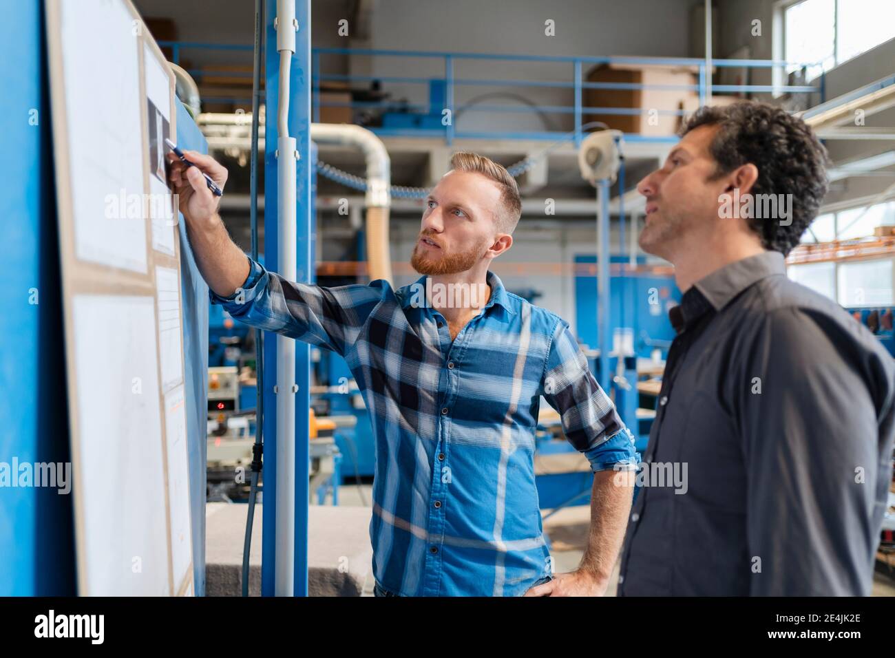 Two carpenters talking over documents in production hall Stock Photo - Alamy