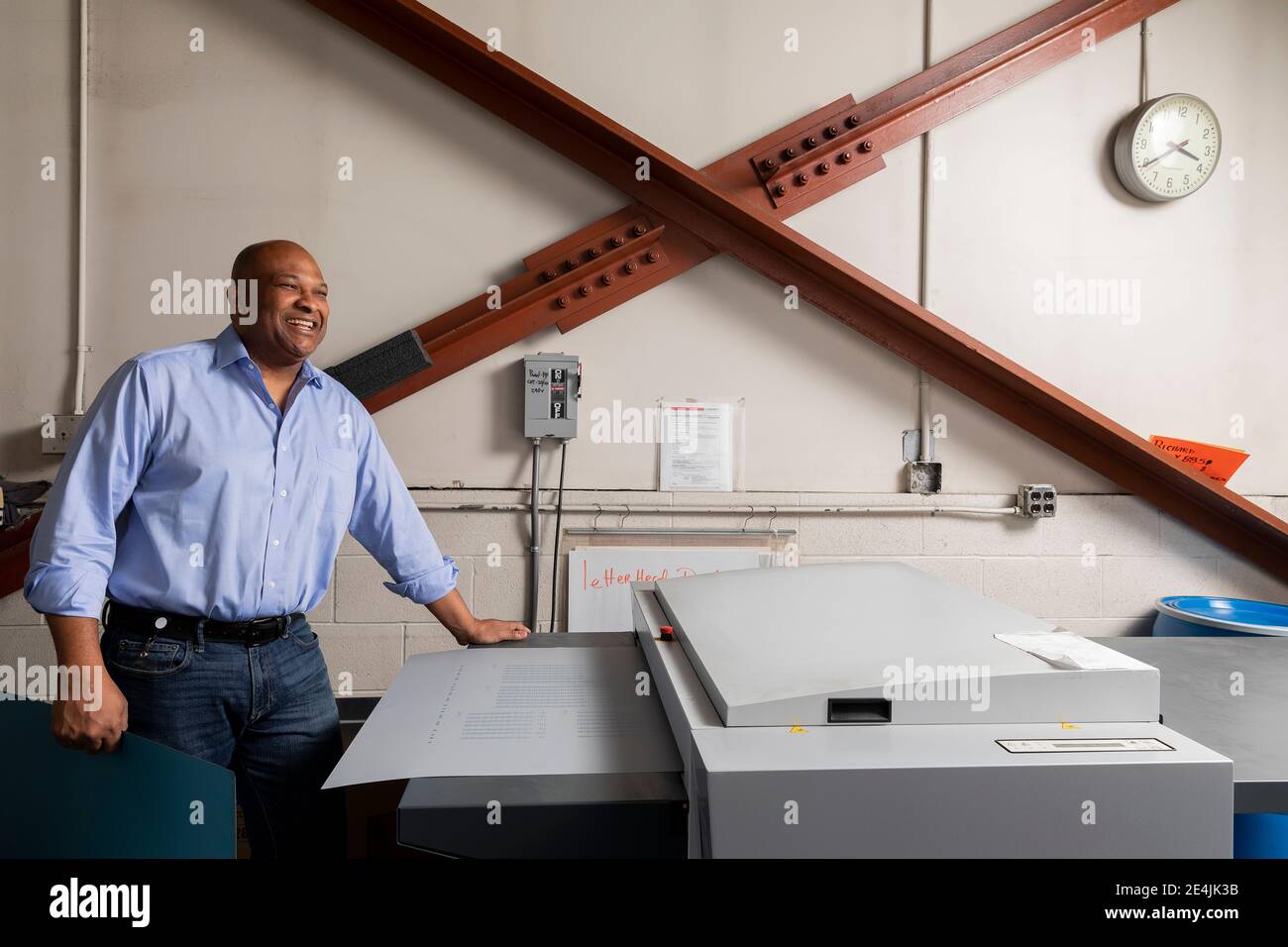 Supervisor examining paper while standing by print machine in shop ...