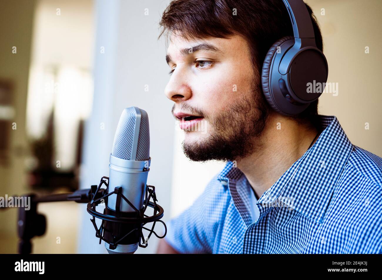 Singer with headphones using microphone while singing at recording ...