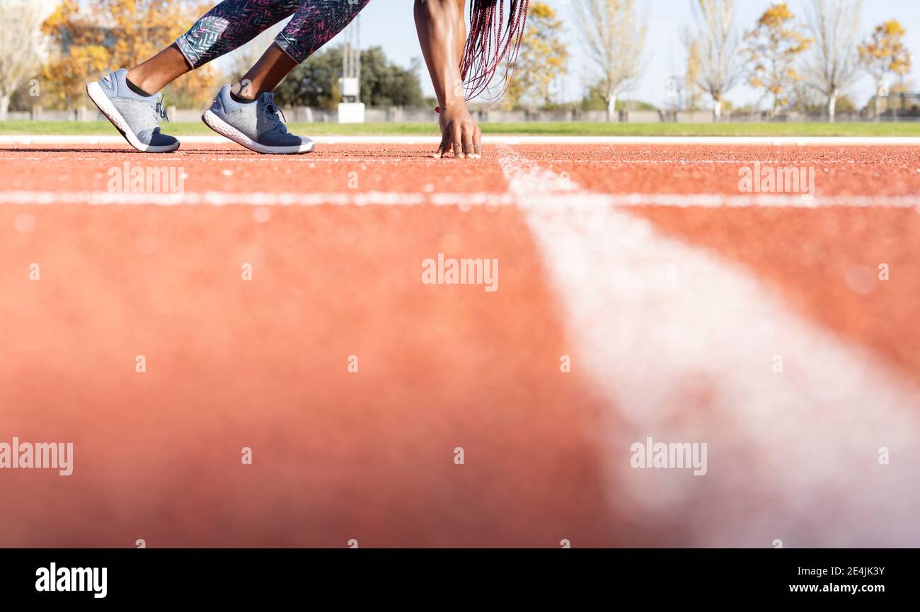 Sportswoman at start line on running track during sunny day Stock Photo ...