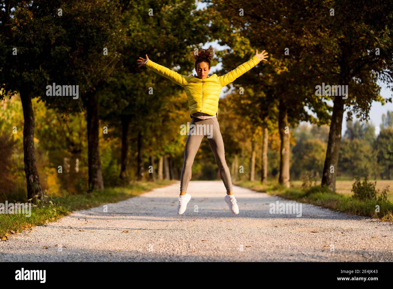 Female athlete with arms outstretched jumping while exercising at park ...