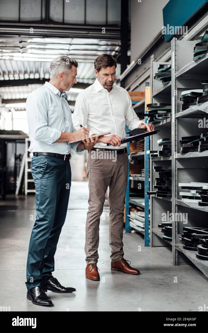 Male inspectors checking equipment while standing in workshop at ...
